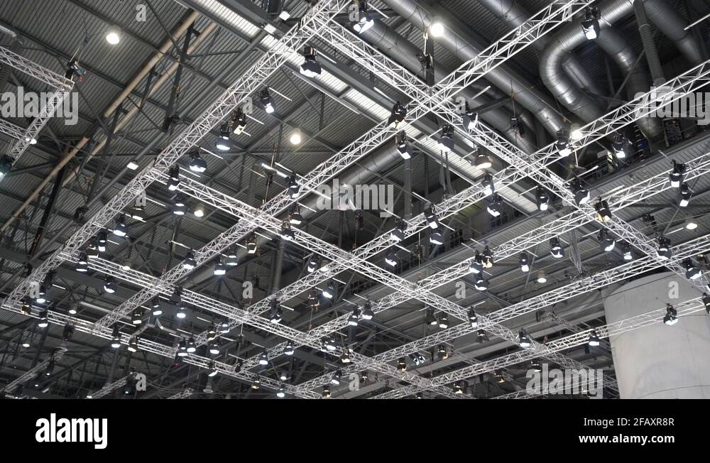 Huge trusses hanging on a exhibition hall ceiling. Many lights are ...