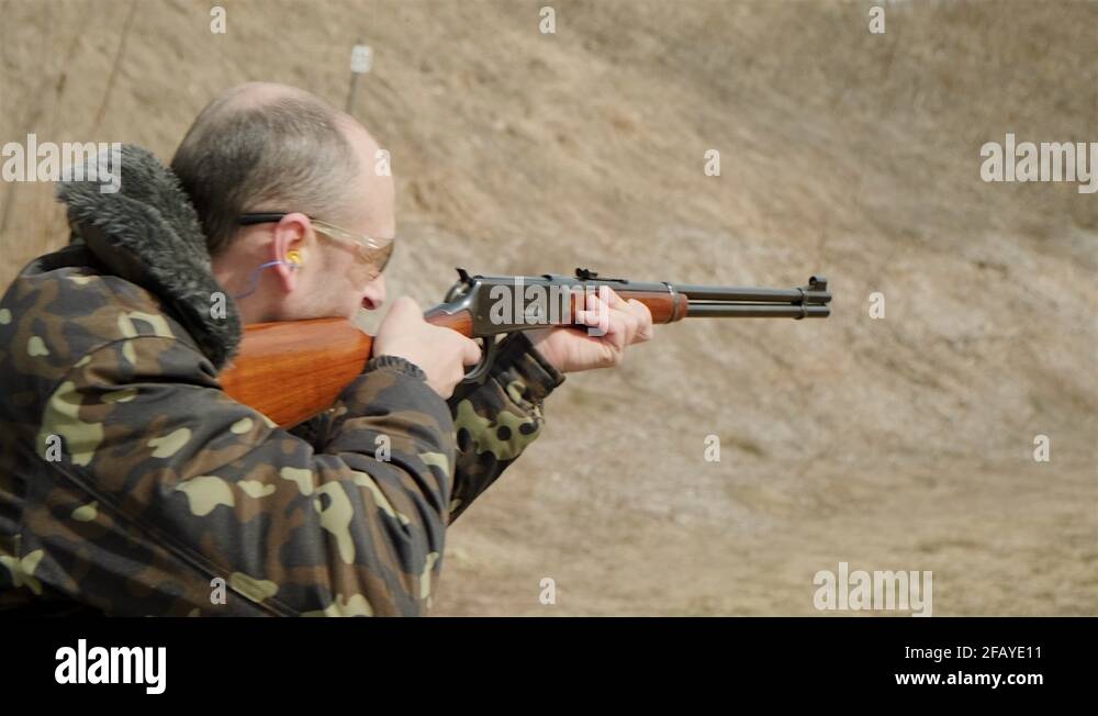 A man shooting a lever-action repeating rifle outdoors. Slow Motion 4K ...