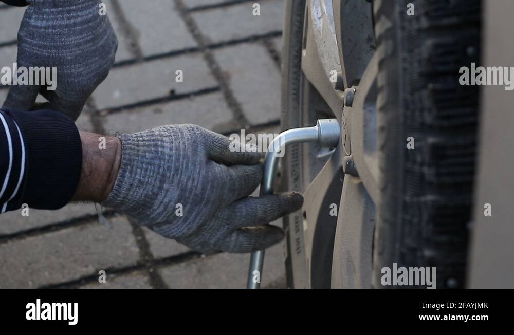 Man Unscrew the nuts to remove and change the wheel of a car Stock ...