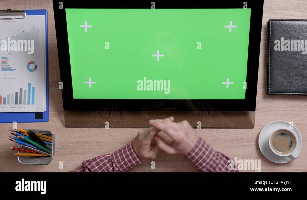 Man's hands touch the top right corner of a green screen on touch ...