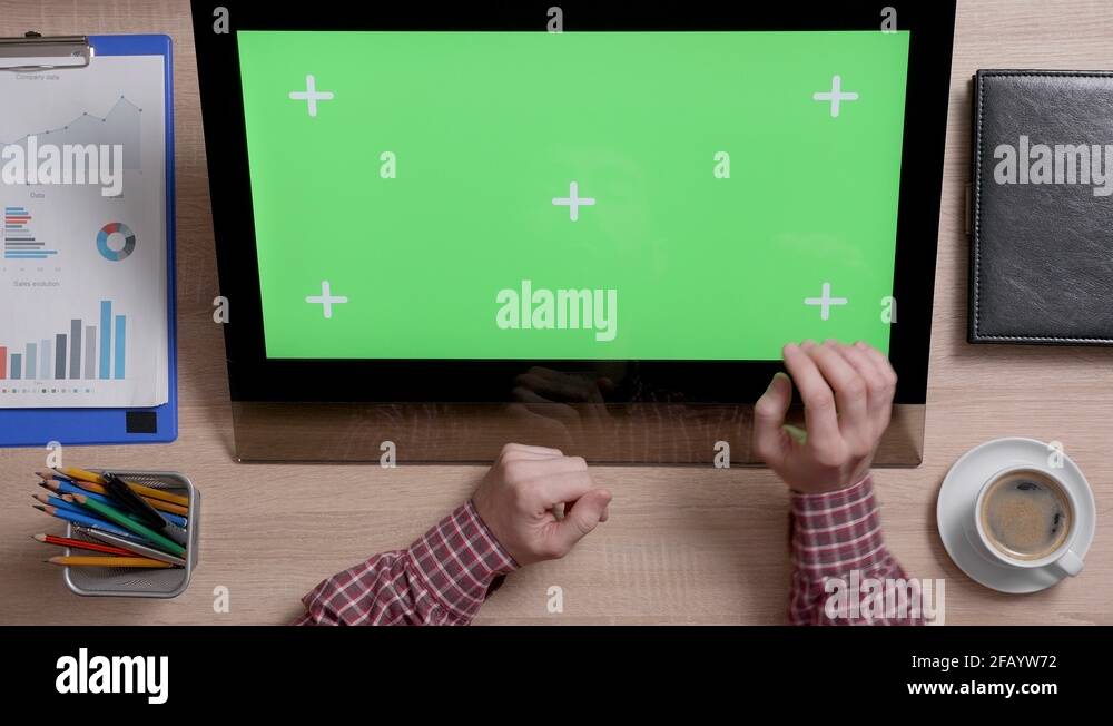 Top view of a man's hands touch the bottom right corner of a green ...