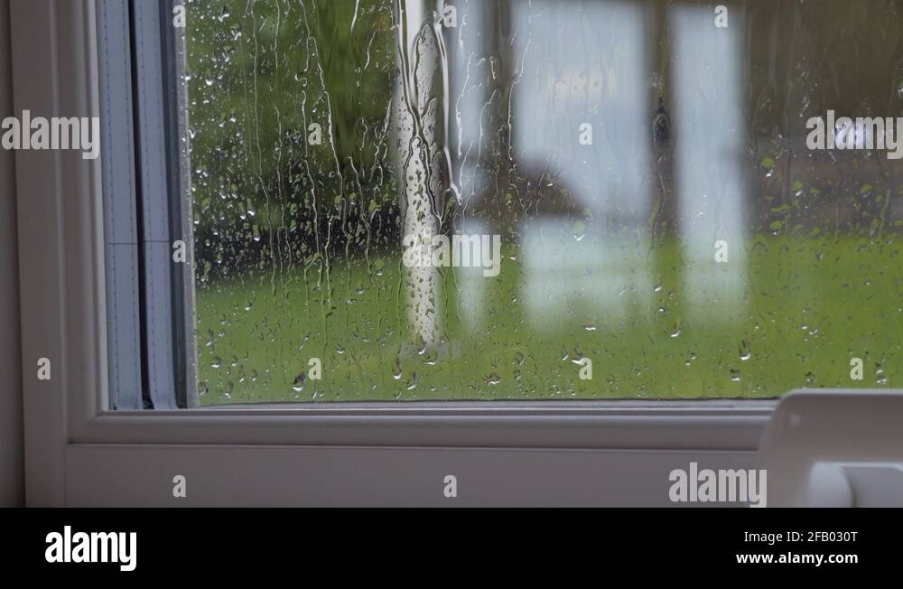 Static shot of rain gentle hitting a window frame with a reflection ...