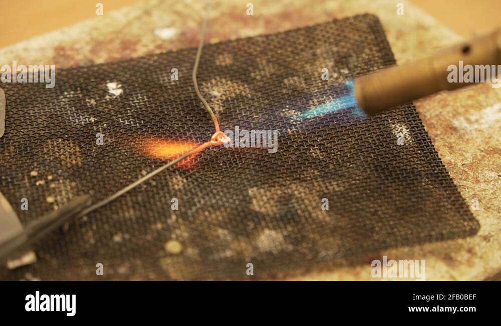 Soldering metal wires with butane gas flame burner - close up shot in ...