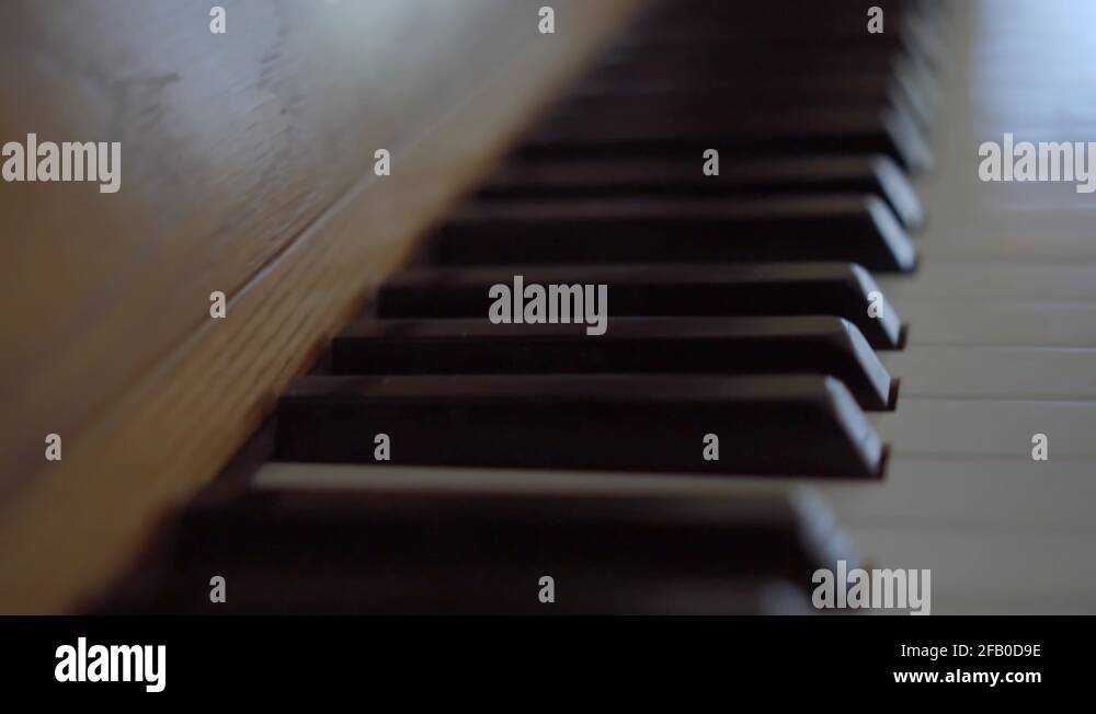 Camera sliding left to right of a wooden stand up piano keyboard with a ...