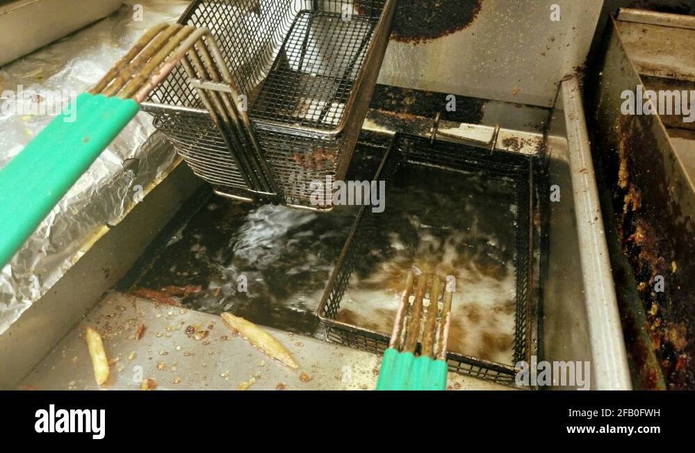 A used and dirty fryer with fries in the oil and an empty bin Stock ...