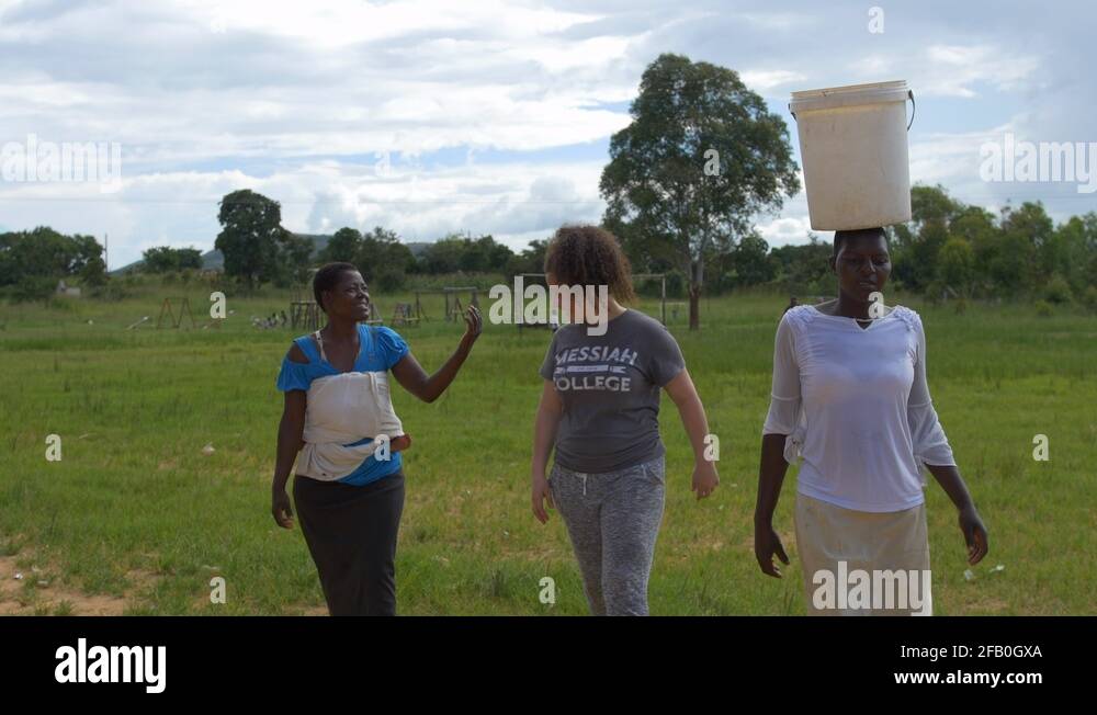 An African Woman Walks While Balancing a Bucket of Water on Her Head ...