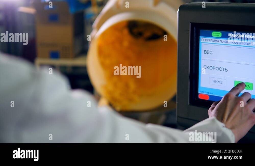 Food factory worker types on a machine, controlling a conveyor with ...