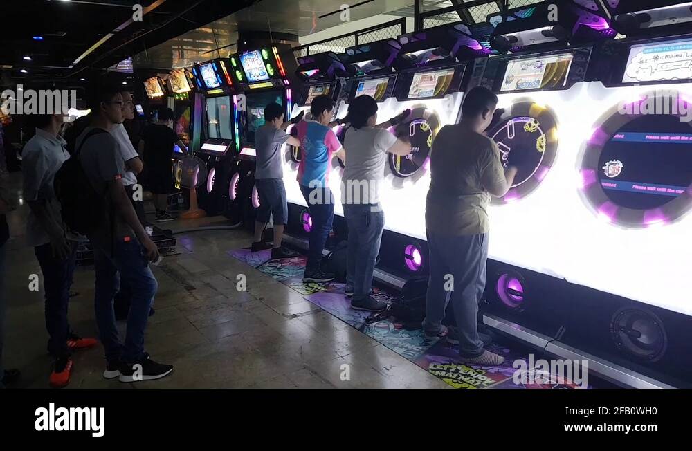 4 Asian kids Playing Arcade Machine Drum Music Game And Pushing Bright ...