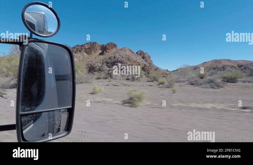 Side view of the rear-view mirror of an overland RV driving off road in ...
