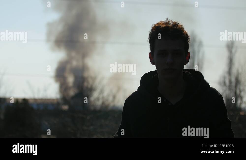 silhouette of upset man on the sky background with black thick smoke ...