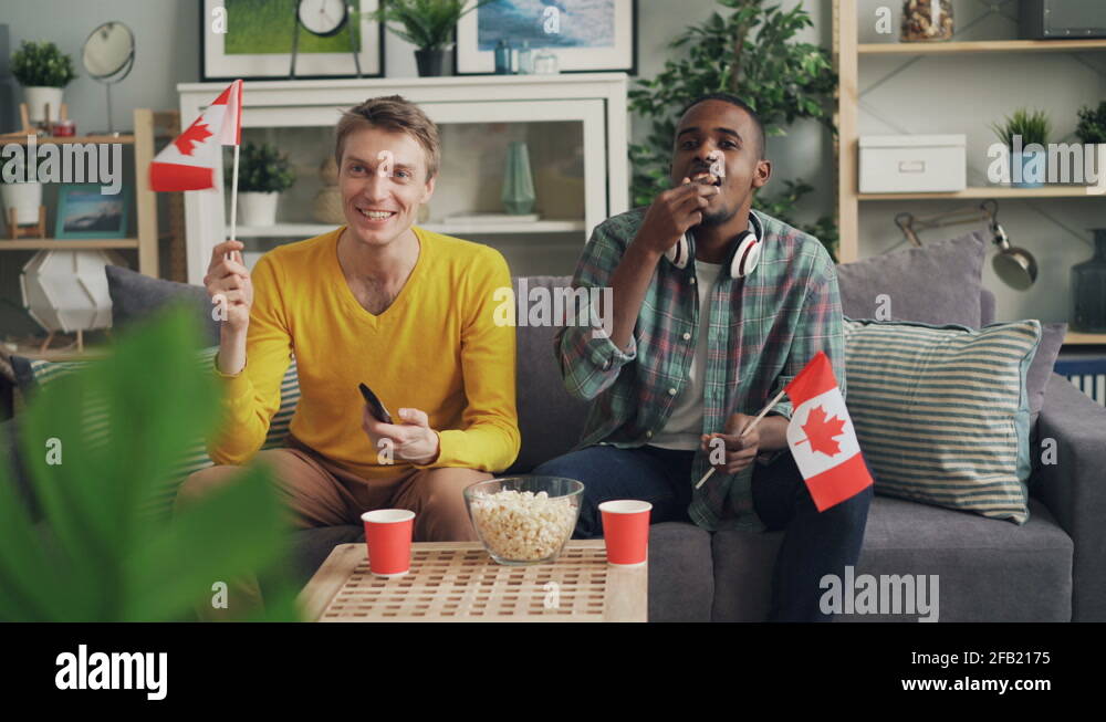 Handsome guys sports fans are watching competition on TV holding ...