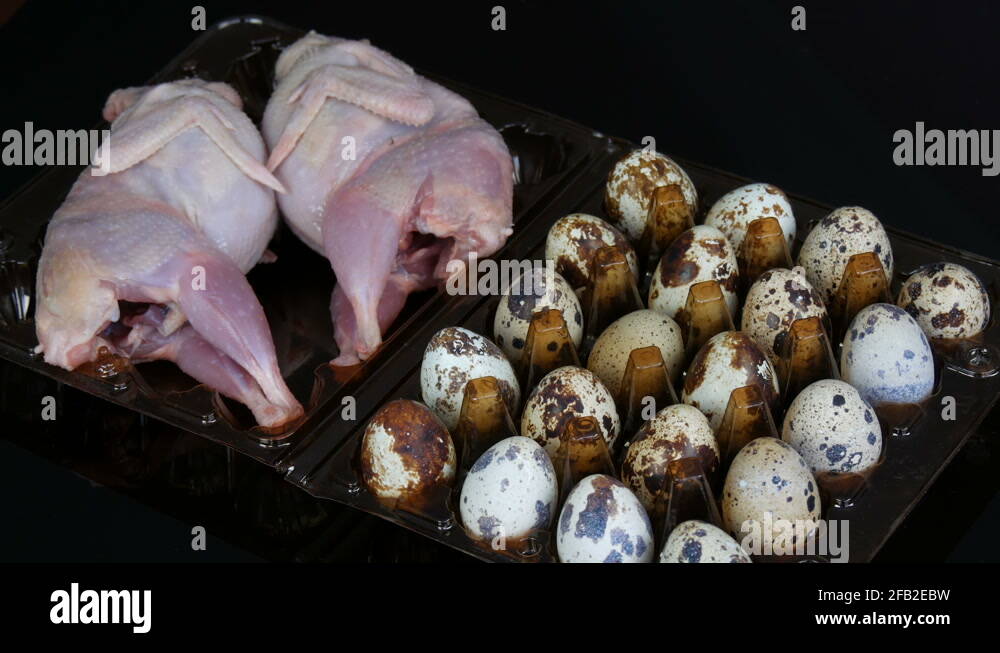 Fresh meat of quail in a plastic brown tray next to the quail eggs on ...