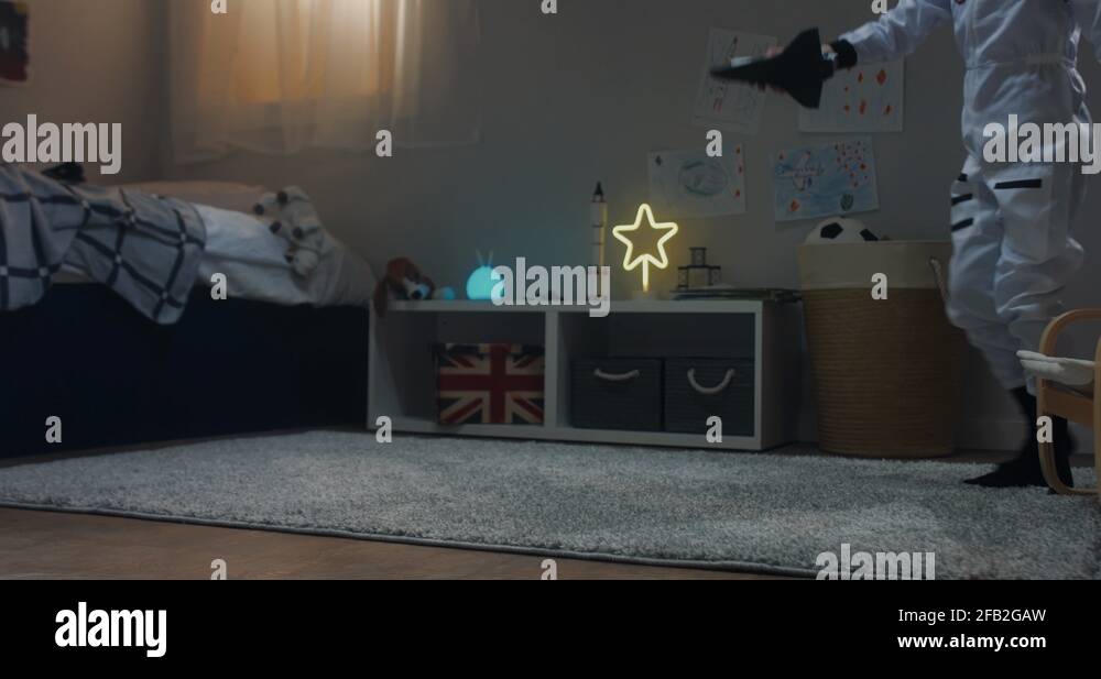 Cute girl wearing astronaut suit playing with toy shuttle space ship ...