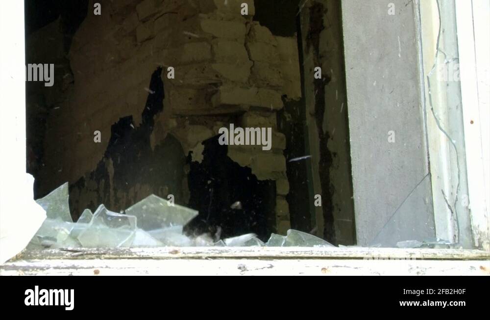 Soldier in military uniform with guns is firing from window of ruined ...