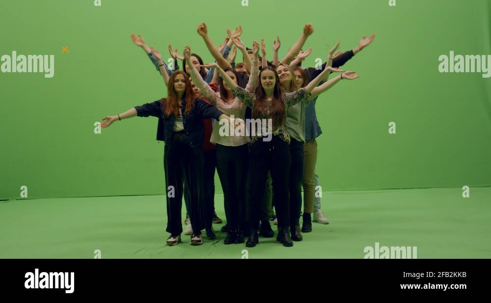 Front view group of young people standing and clapping hands in the air ...