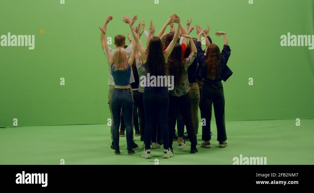 Back view group of young people standing and clapping hands in the air ...