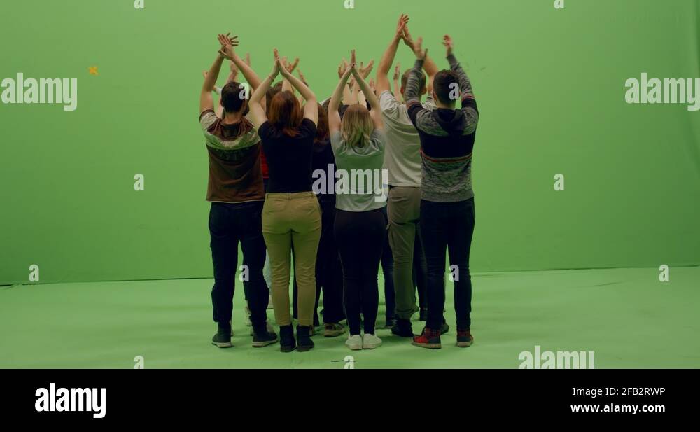 Back view group of young people standing and clapping hands in the air ...