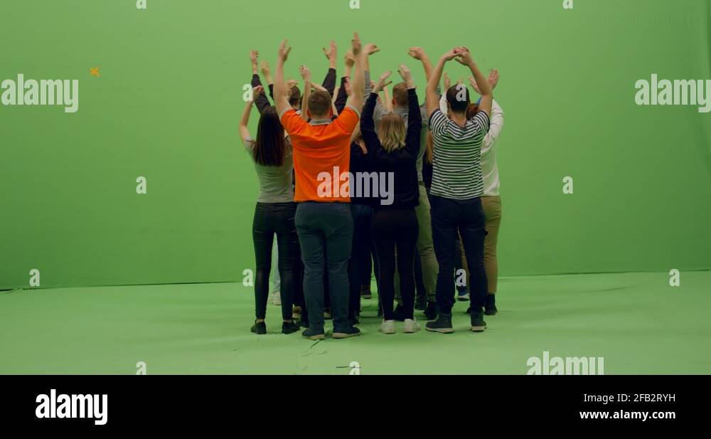 Back view group of young people standing and clapping hands in the air ...