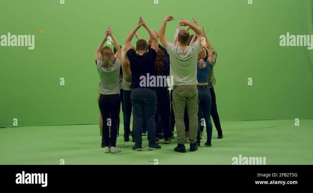 Back view group of young people standing and clapping hands in the air ...