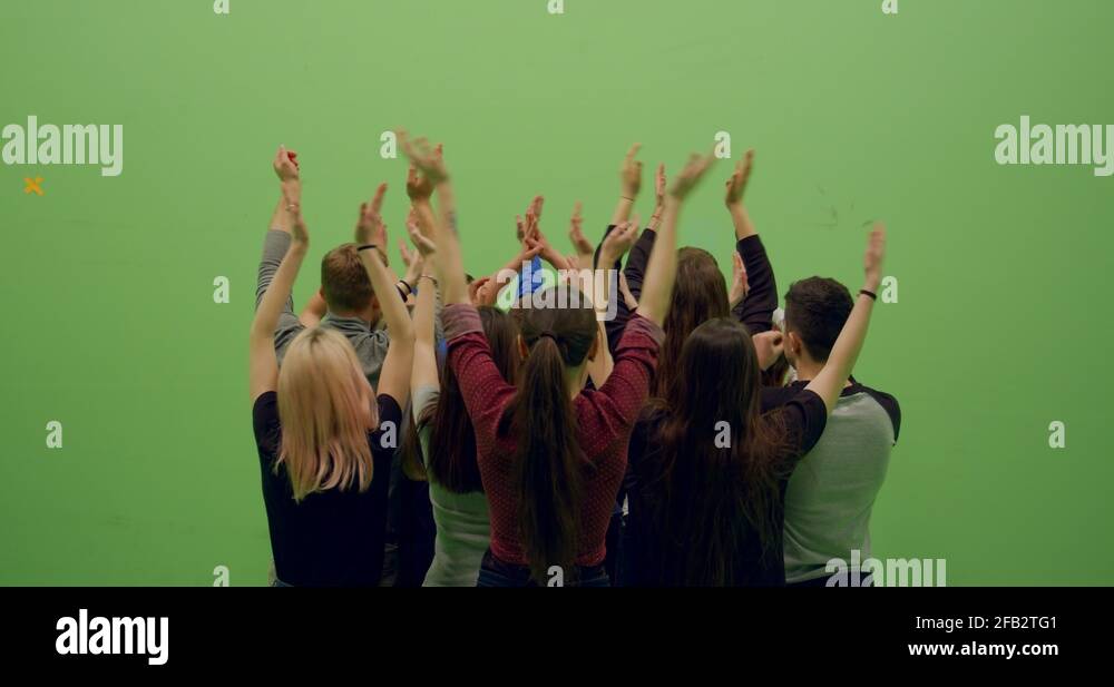 Back view group of young people standing and clapping hands in the air ...