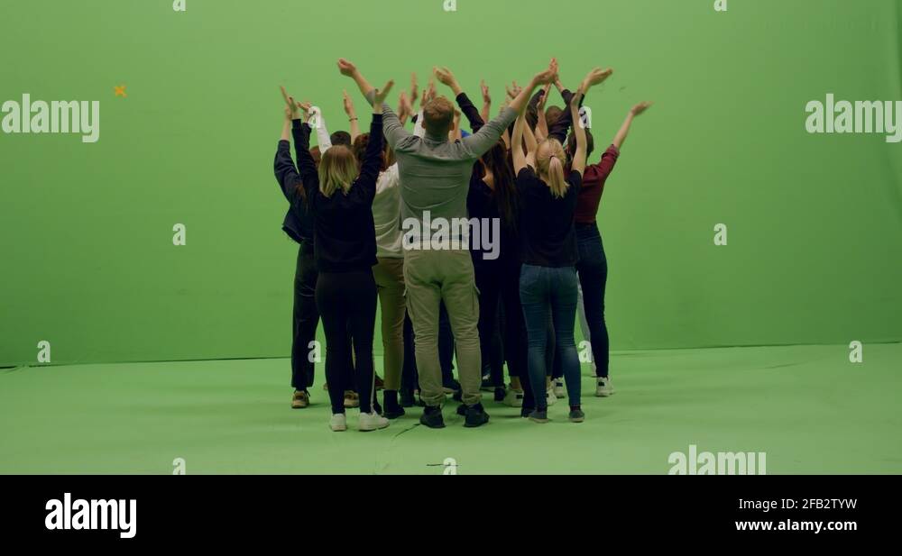 Back view group of young people standing and clapping hands in the air ...