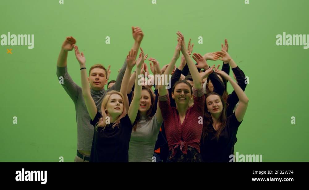 Front view group of young people standing and clapping hands in the air ...