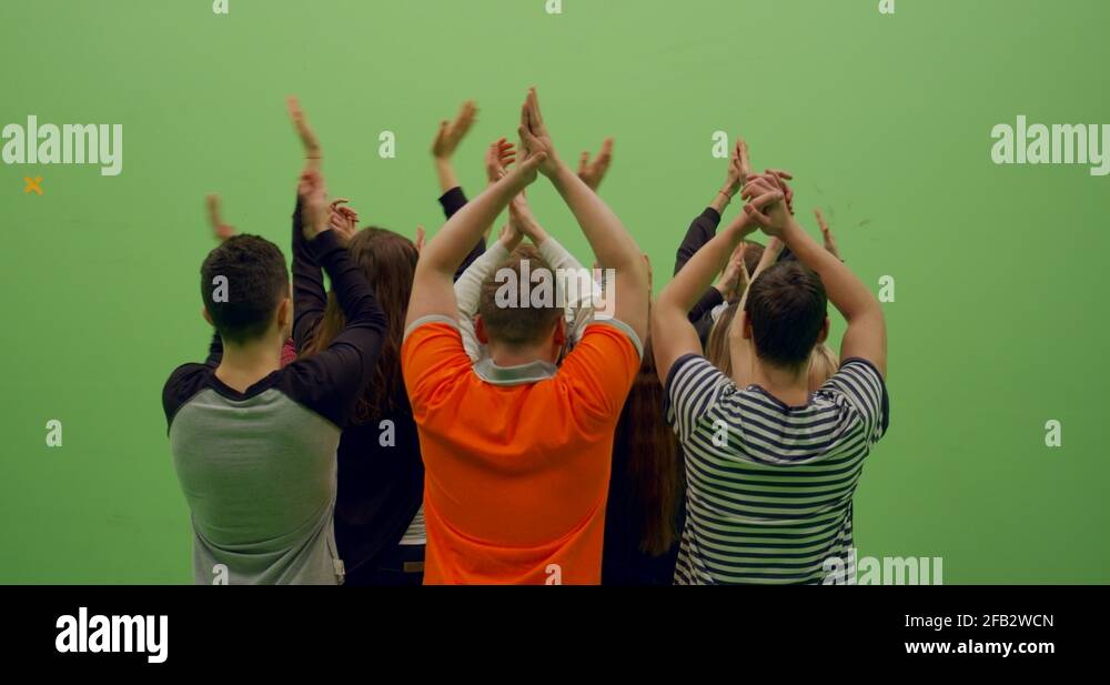 Back view group of young people standing and clapping hands in the air ...