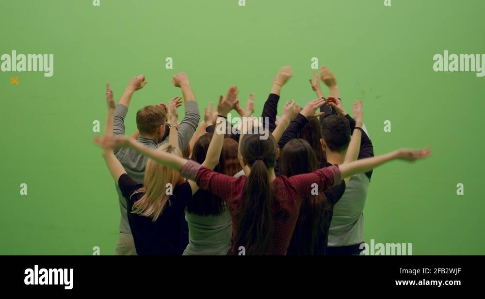 Back view group of young people standing and clapping hands in the air ...