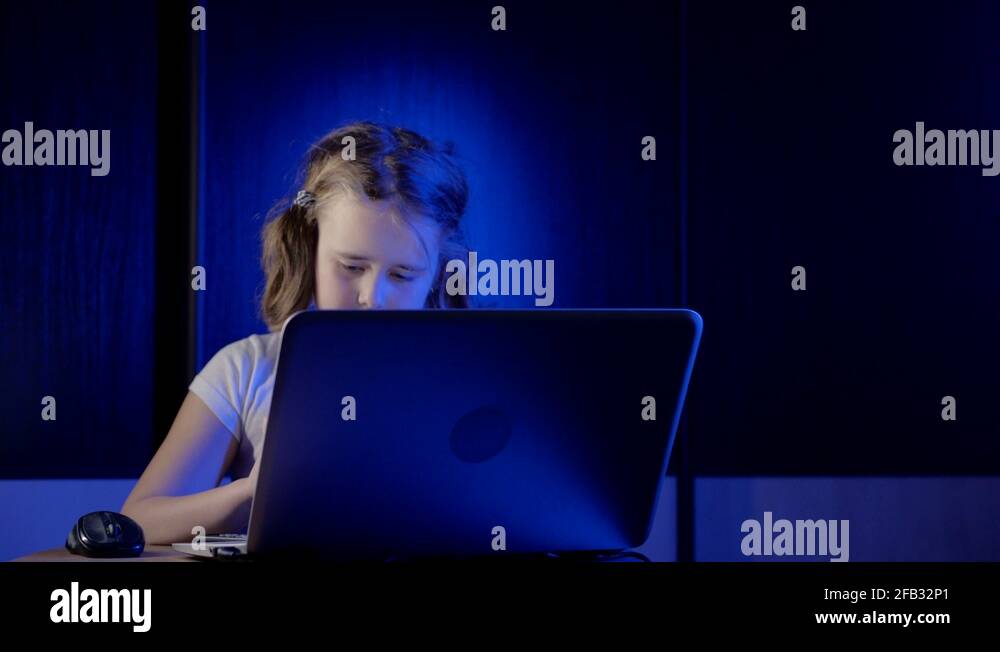 A little girl emotionally online talking on video on a computer late at ...