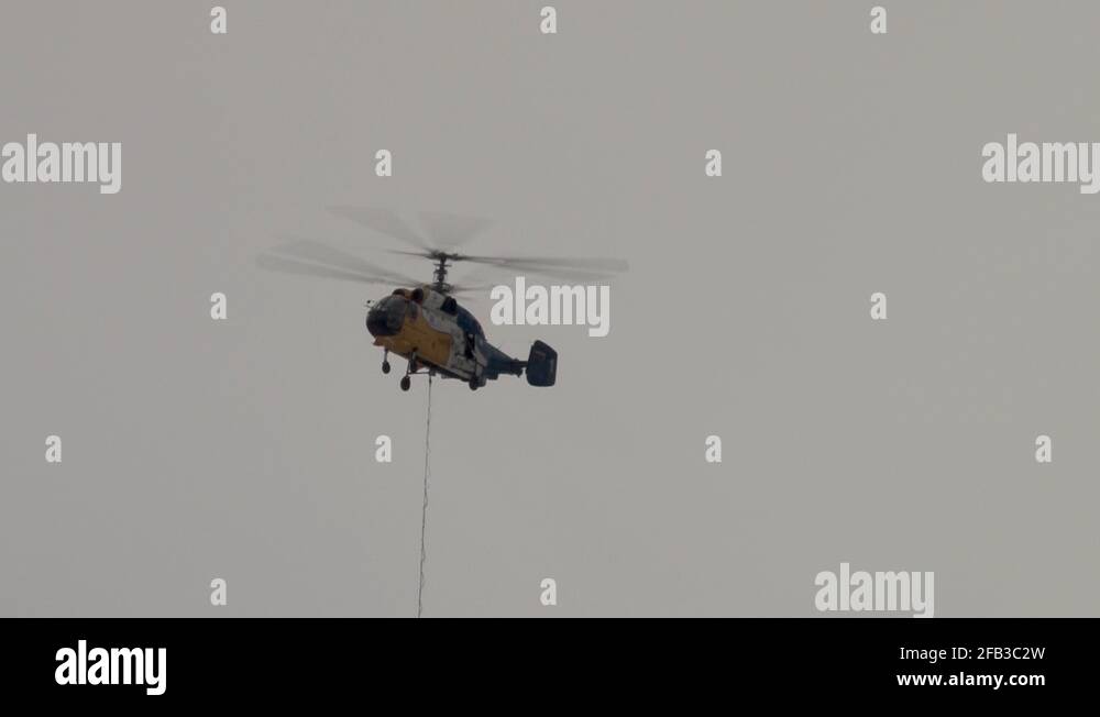 Ka-32 helicopter with load is flying to support of the cable car Stock ...