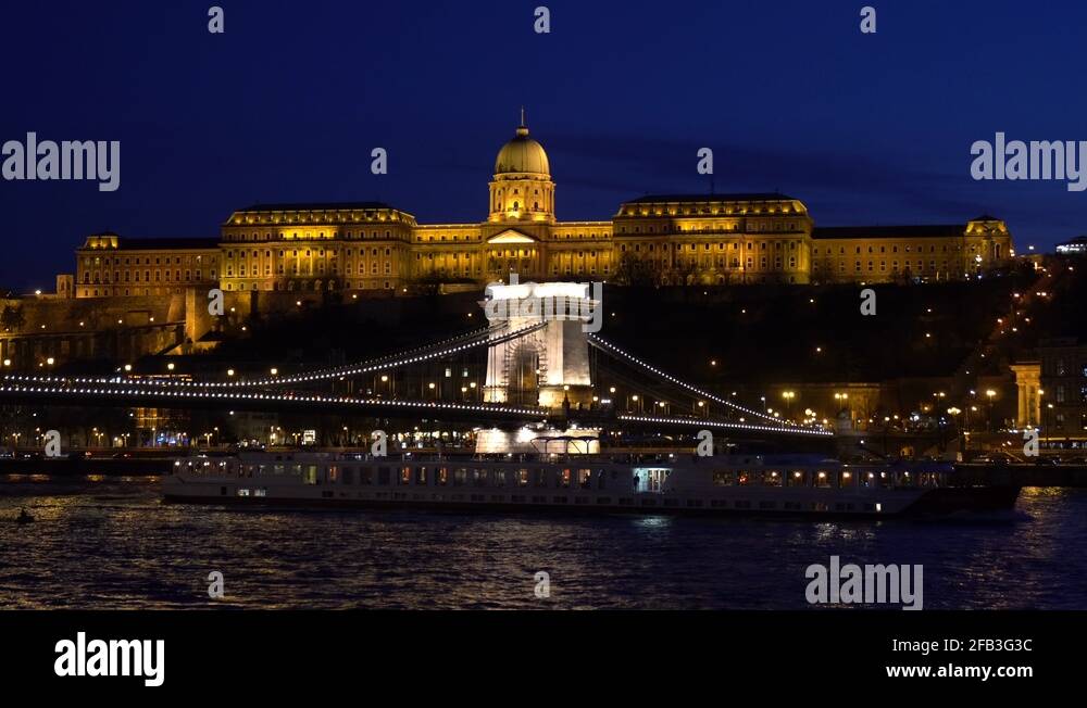 Castle side with chain bridge at evening, lights up as a river cruise ...