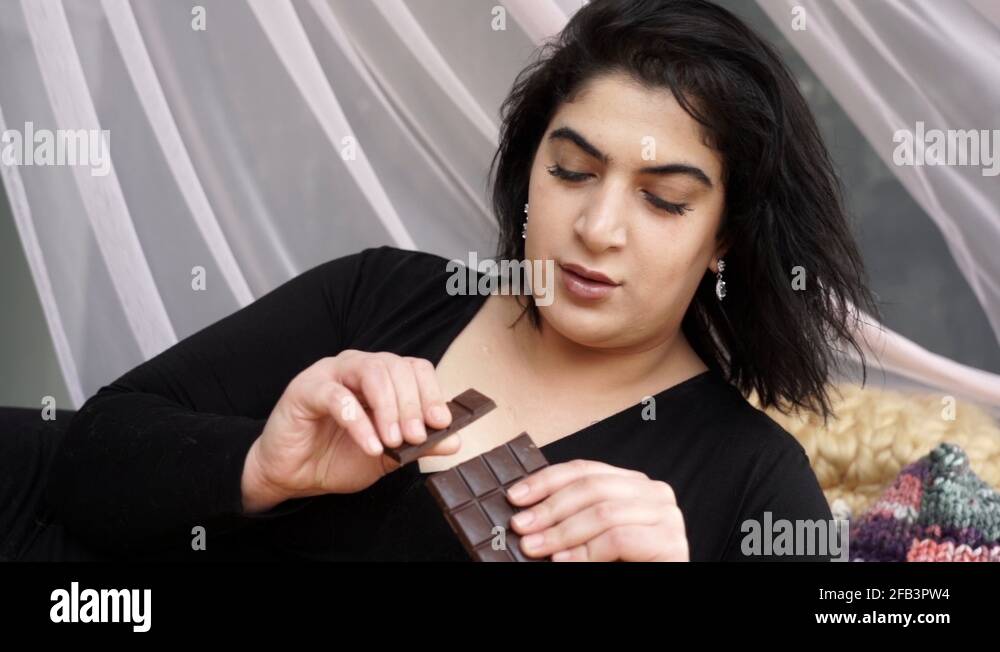 Attractive plus size model lying on bed eating chocolate Stock Video ...