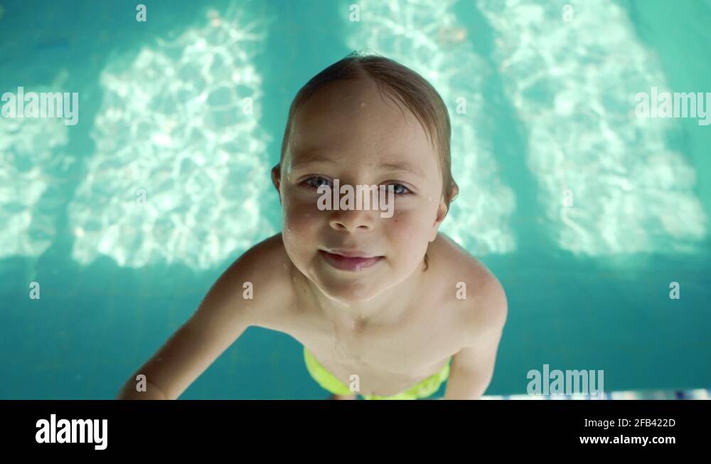 6 year old boy falling into the pool with blue water. Splashes fly in ...