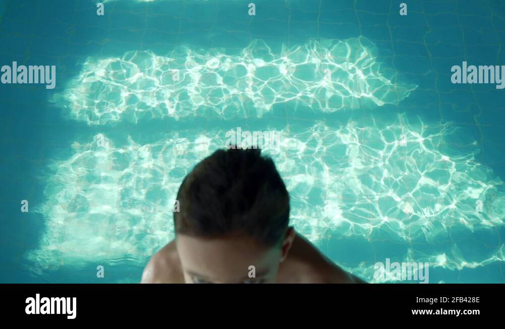 9 year old boy falling into the pool with blue water. Splashes fly in ...