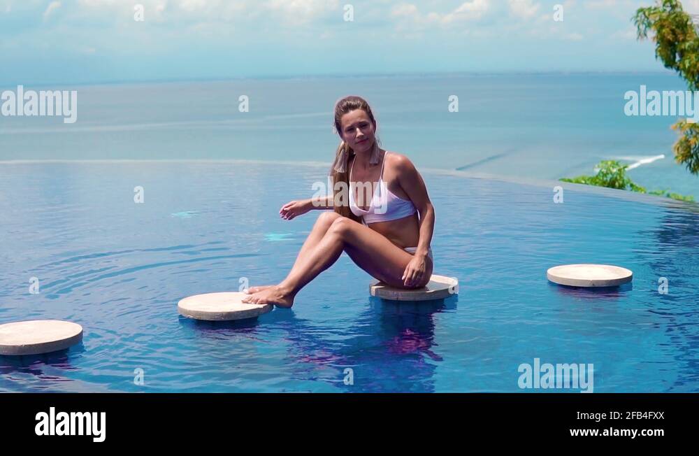 Sexy model in white bikini sunbathing by infinity swimming pool. Luxury travel Stock Video ...