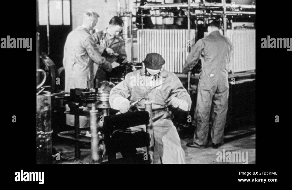 1940s: Man welds as people work behind him in factory. Man welding. Man ...