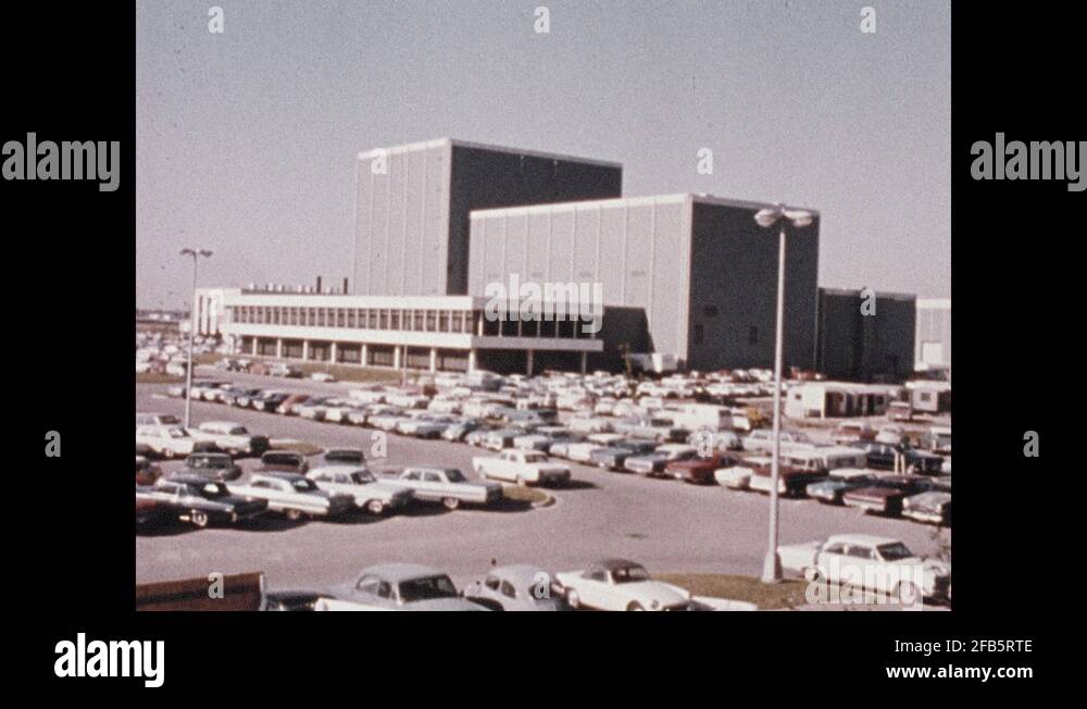 1960s: Exterior of NASA facility. Pan of men closing door to vacuum ...