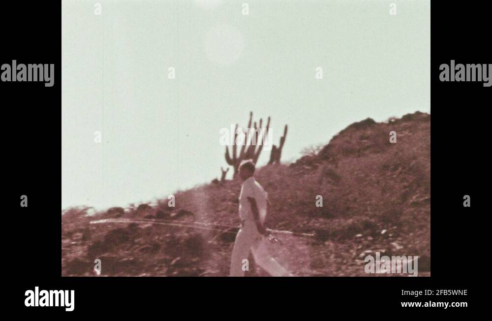 1960s: MEXICO: man with fishing rod walks across cliff path. Waves on ...