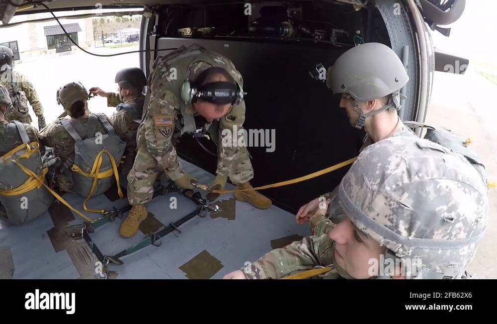 U.S. Army jumpmaster attaches parachutists static line to UH-60 Black ...