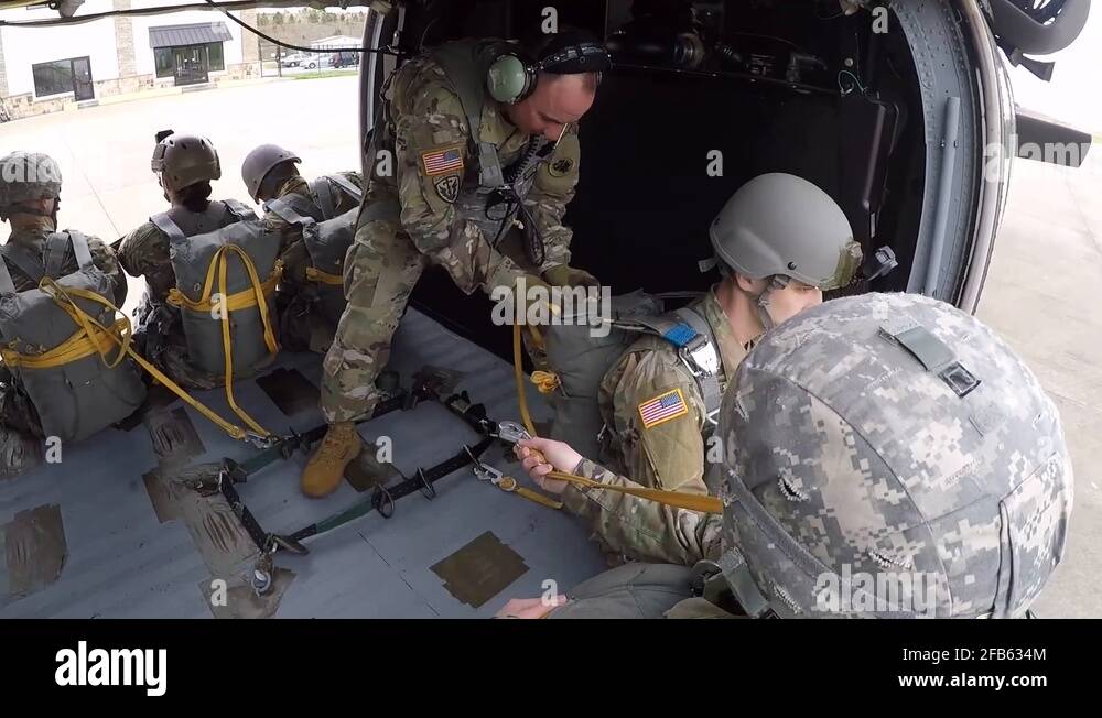 U.S. Army jumpmaster attaches paratroopers static line to UH-60 Black ...