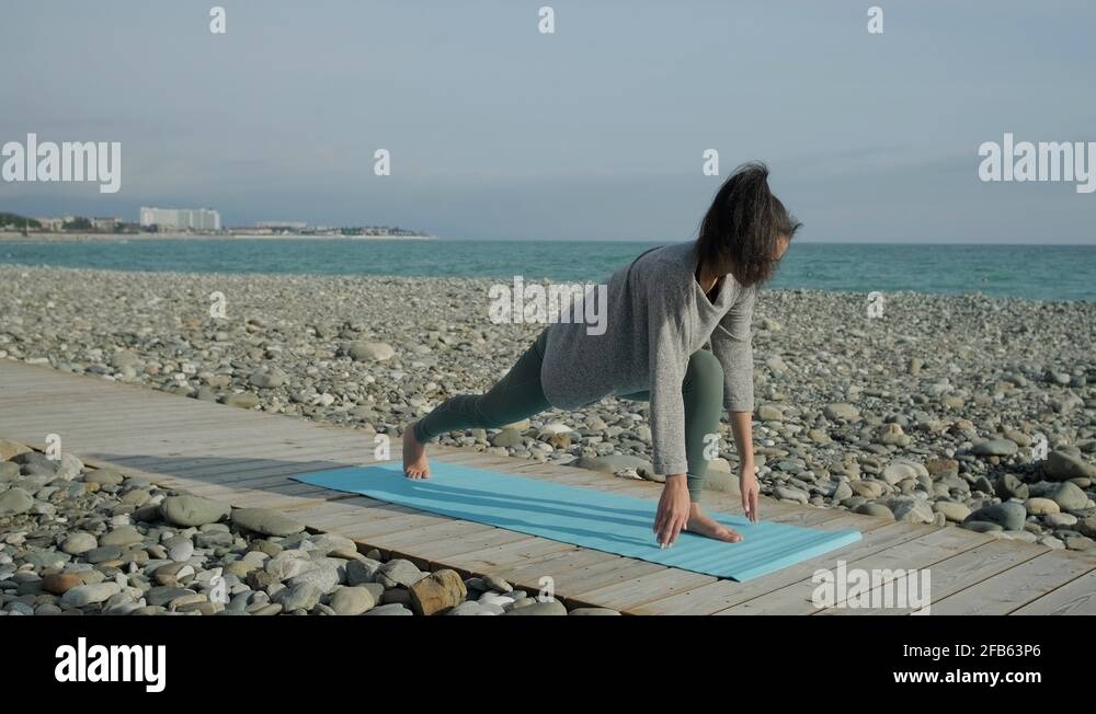 Pretty sporty teen girl is making yoga asanas in sea beach in daytime ...