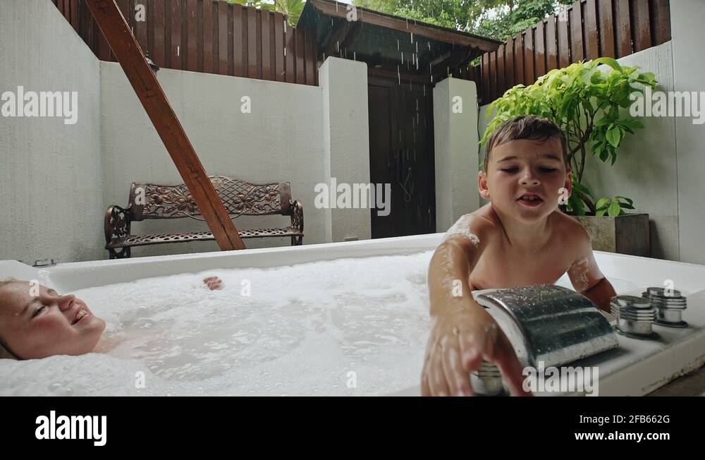 Two young children playing in a spa bath in rain Stock Video Footage ...