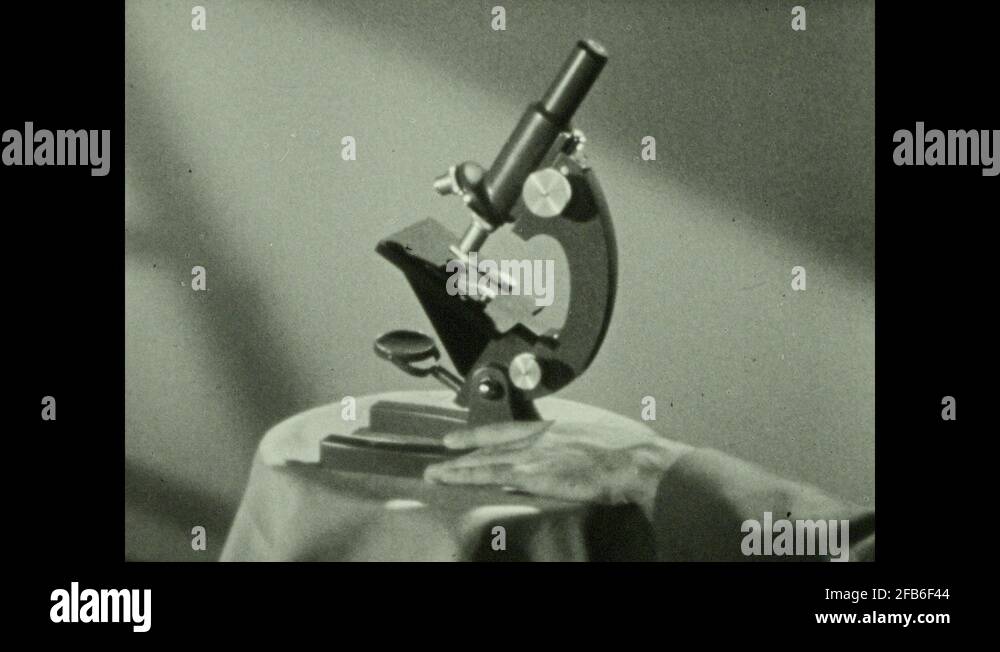 1940s: Hand touches microscope on table, titles appear on screen Stock ...