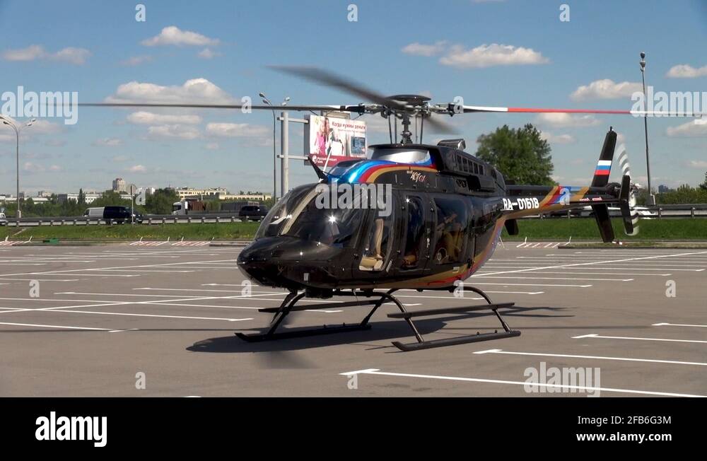 Bell 407 helicopter with rotating main rotor blades in the parking lot ...