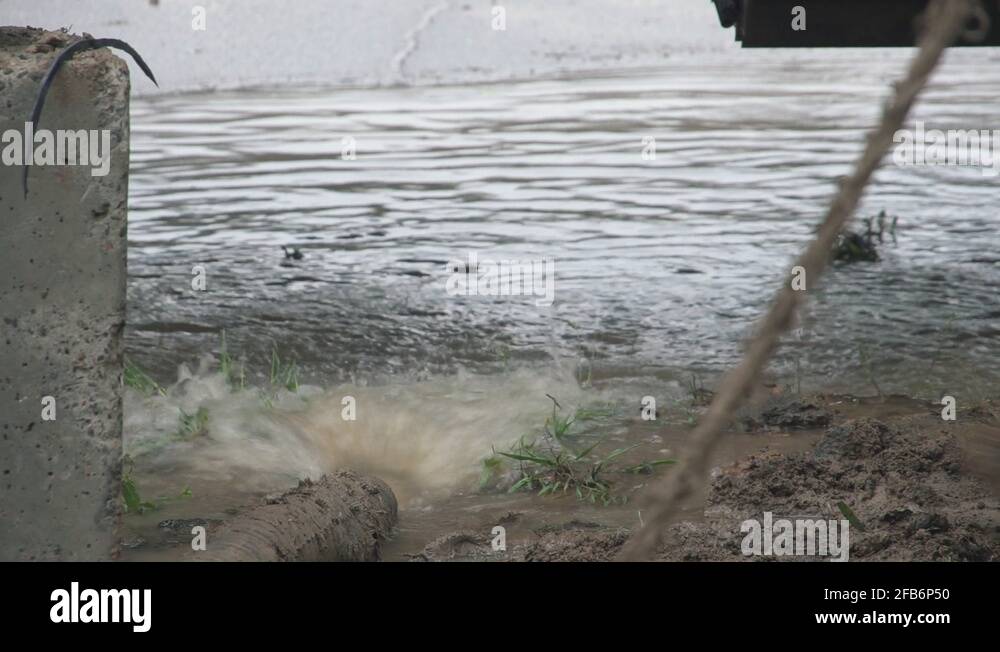 adult worker in a dirty uniform washing hands under water from a tube ...