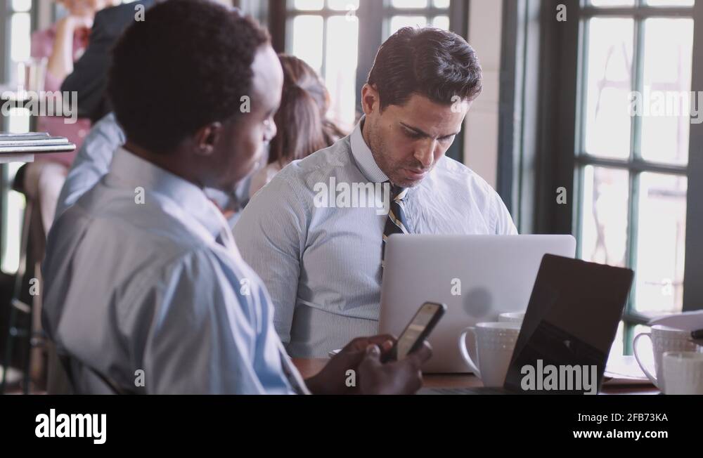 Two Businessmen Having Informal Meeting Around Table In Coffee Shop ...
