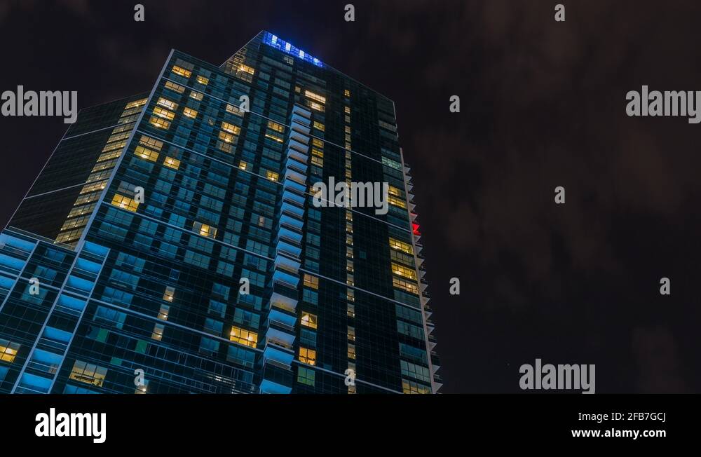 Night Sky with clouds above modern skyscraper with glowing windows ...