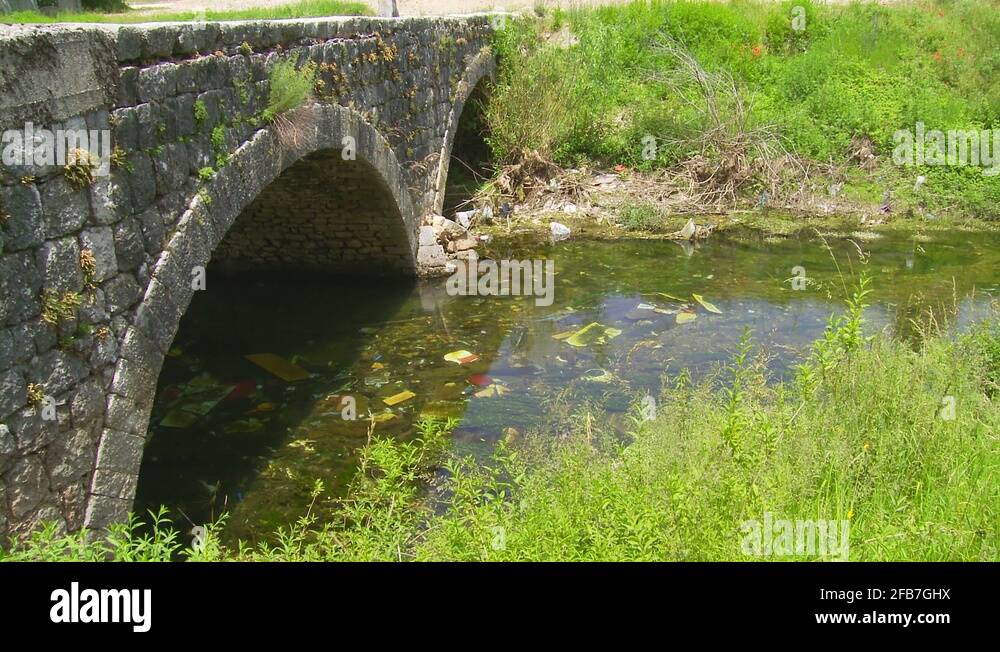 Waste in the river below the old stone bridge. Garbage dumped in a ...