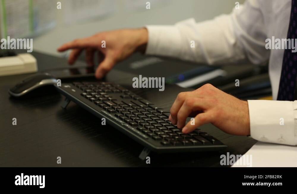 Distracted office worker stops typing to check smartphone during office ...