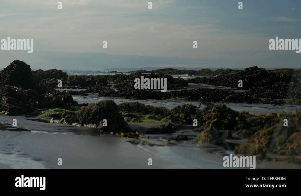 Rocks and rock pools on the beach, with the ocean and waves in the ...